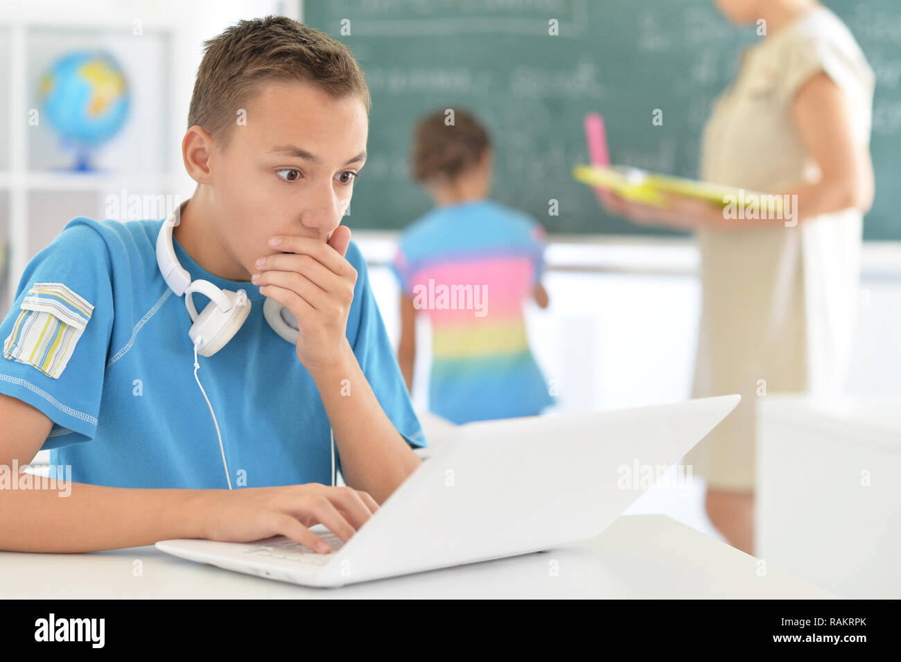 Cute little boy using laptop at classroom Stock Photo - Alamy