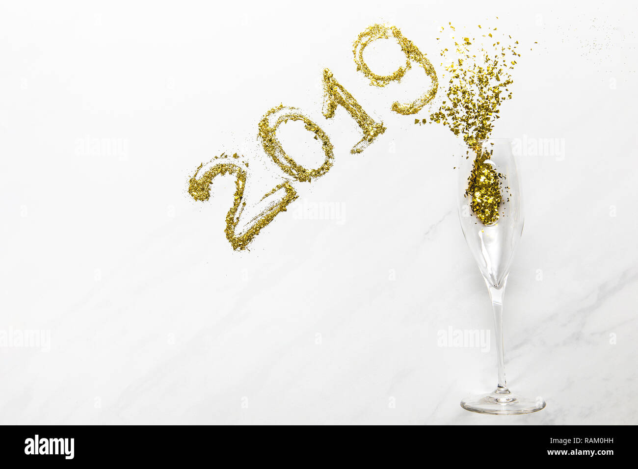 2019 numbers and champagne glass with golden confetti on white ...