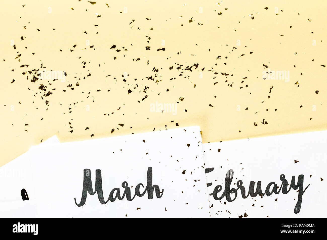 top view of march and february calendar and golden confetti on beige ...