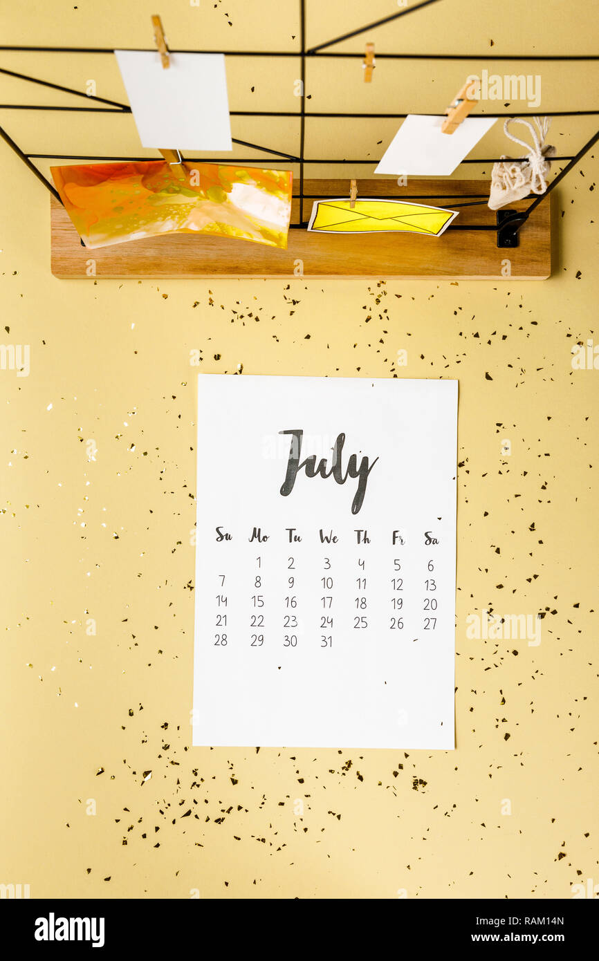 top view of july calendar with golden confetti and cards with ...