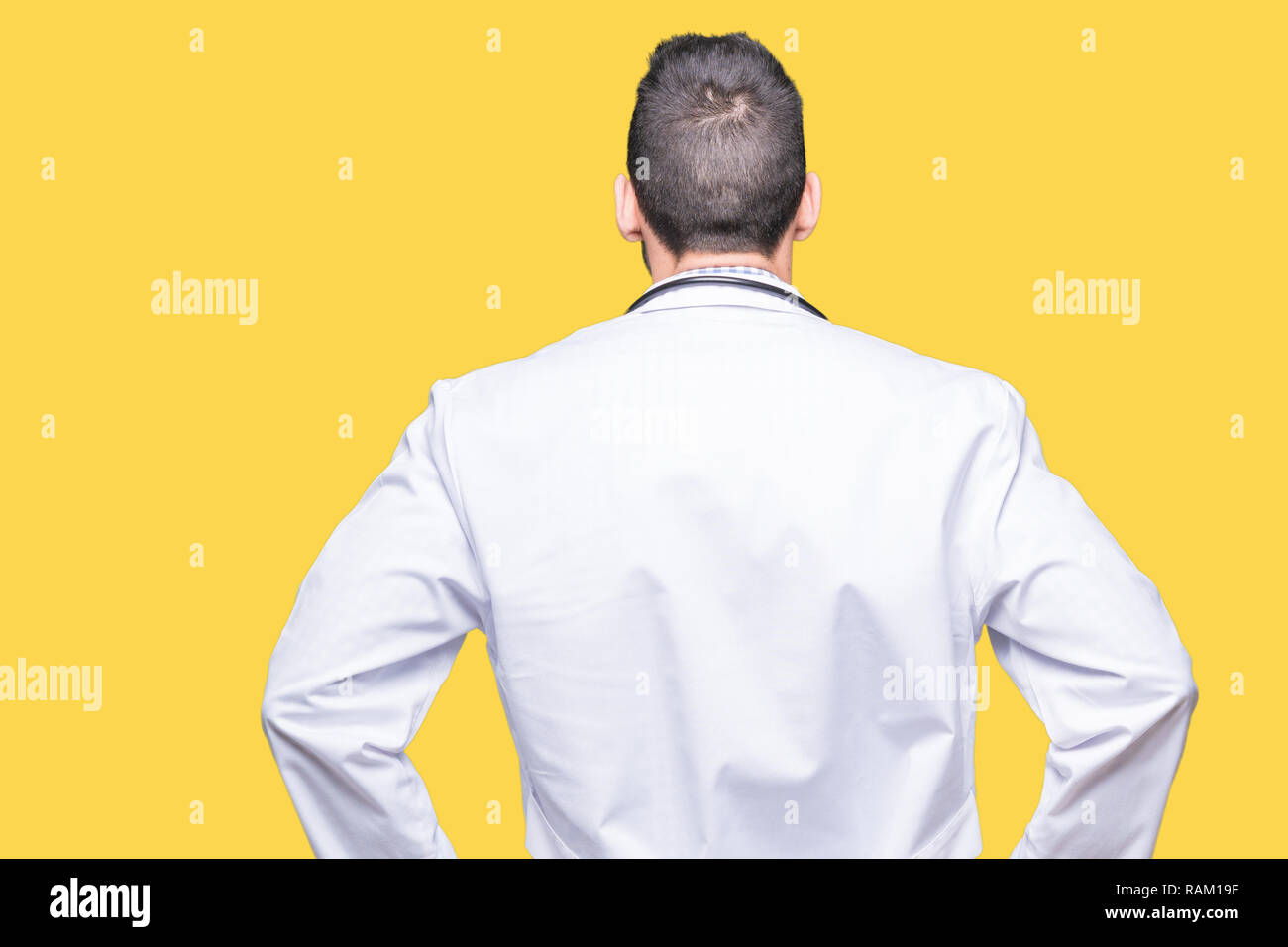 Handsome young doctor man over isolated background standing backwards ...