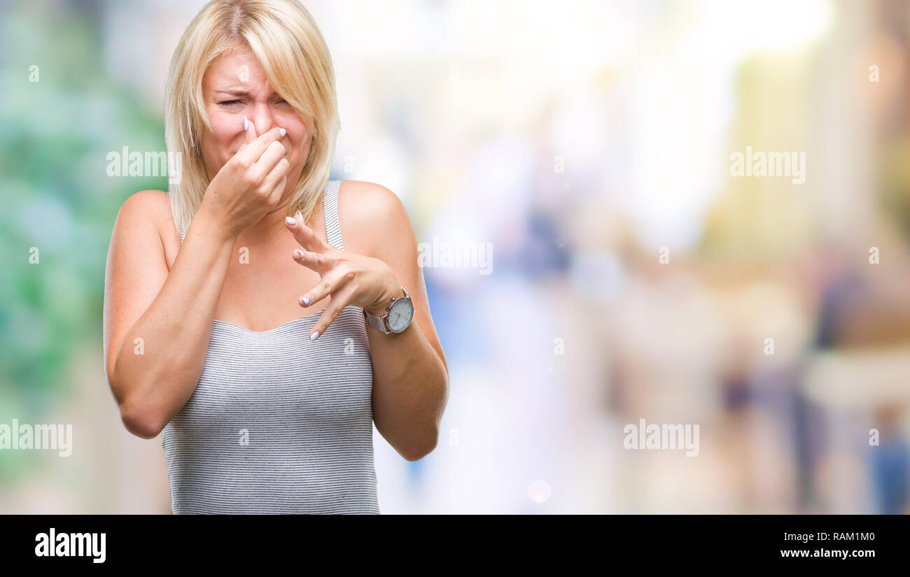 Young beautiful blonde woman over isolated background smelling ...