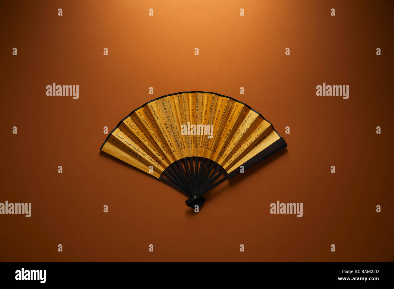 top view of decorative black and golden fan with hieroglyphs on brown ...