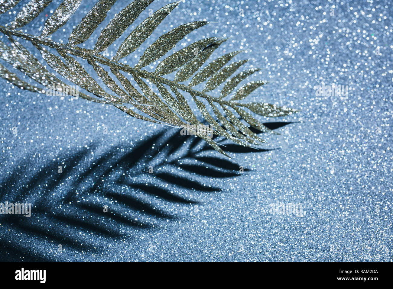 branch decorated by golden glitter and shadow on sparkling surface ...