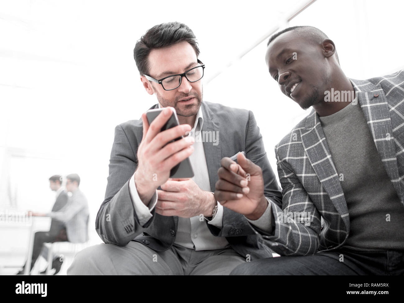 two employees looking at the smartphone screen Stock Photo - Alamy