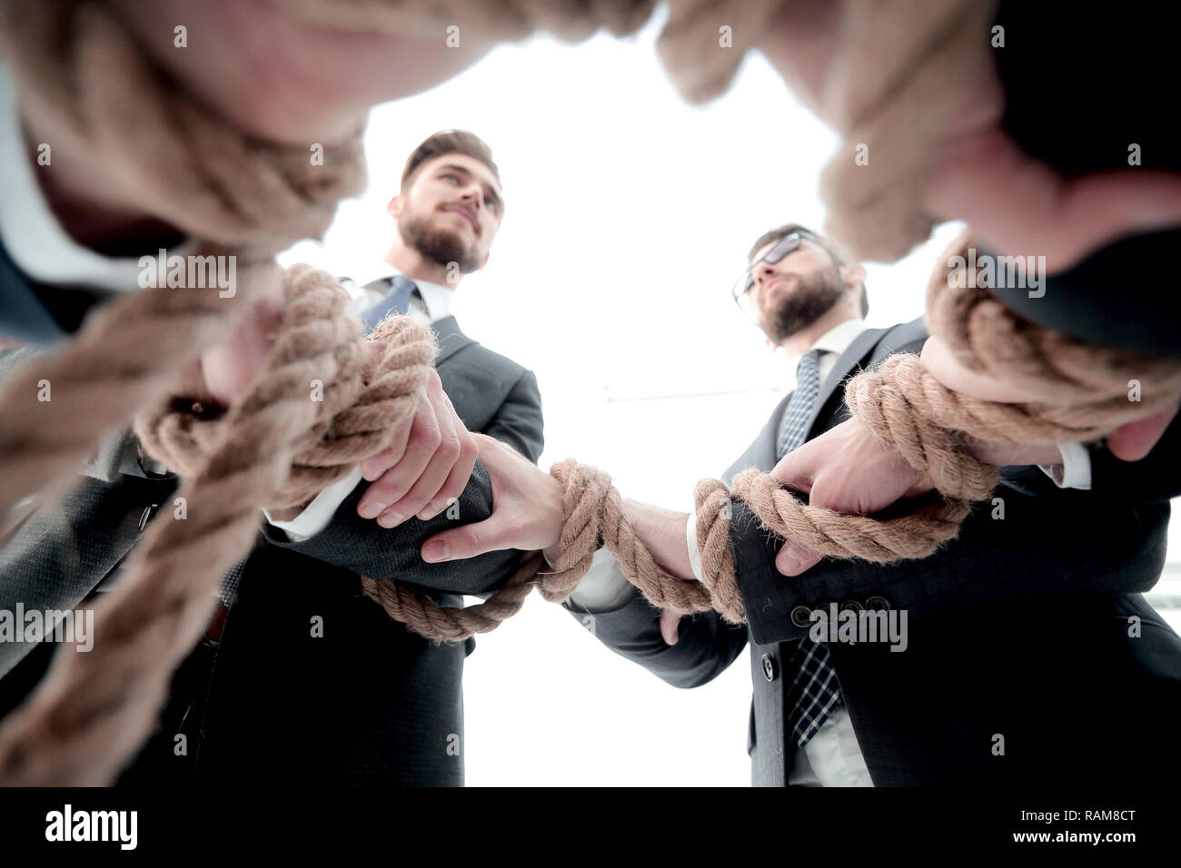 closeup.business team holding strong rope Stock Photo - Alamy