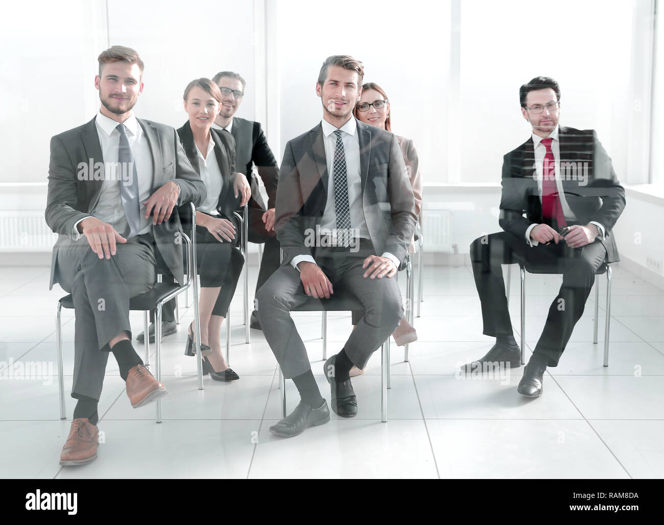 Man and women sitting on chairs in row Stock Photo - Alamy