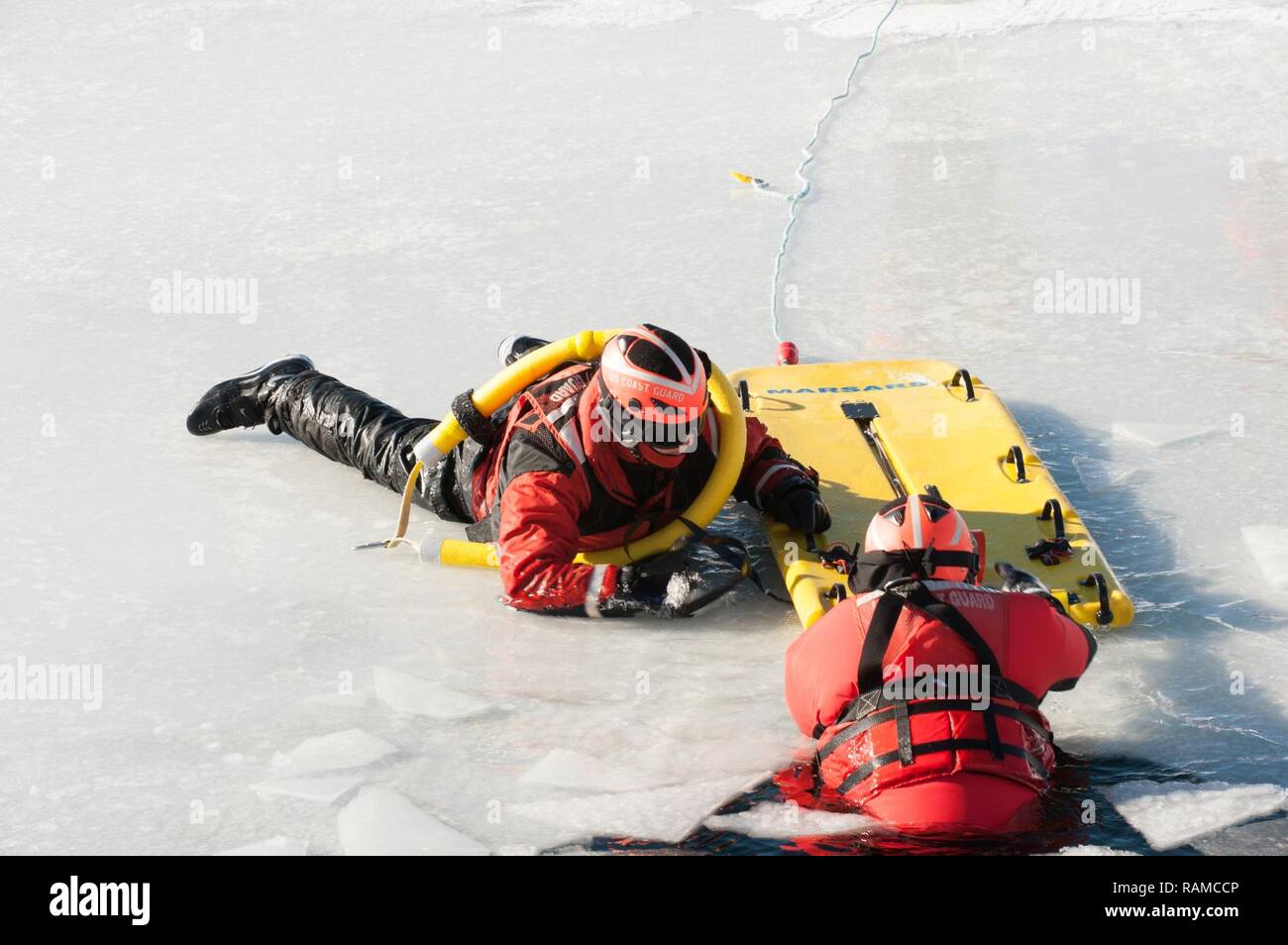 A Coast Guard ice rescue team member uses a rescue shuttle board to ...