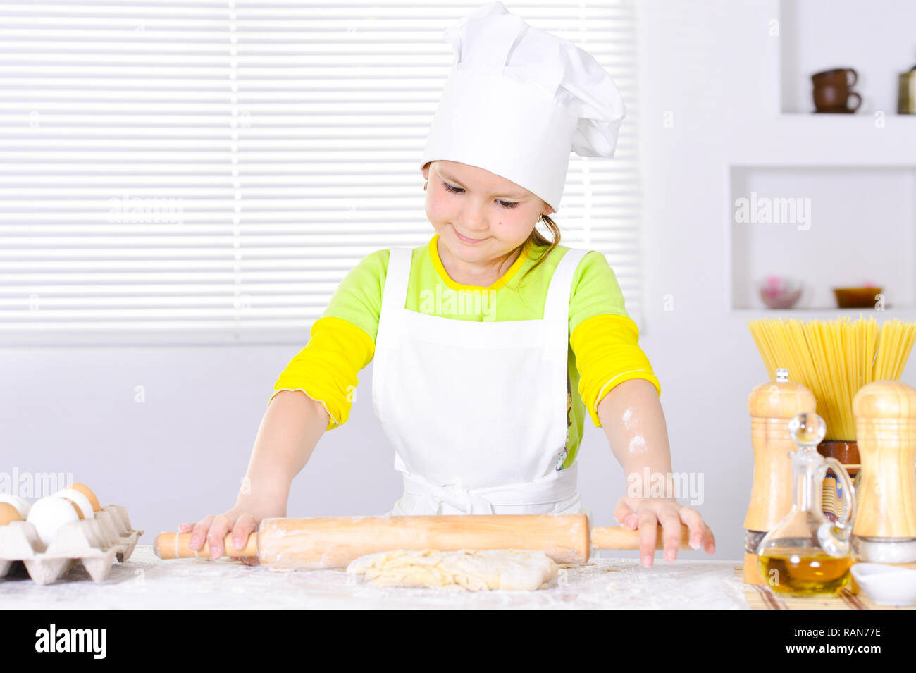Cute little girl in chef's hat baking cake in the kitchen at home Stock ...