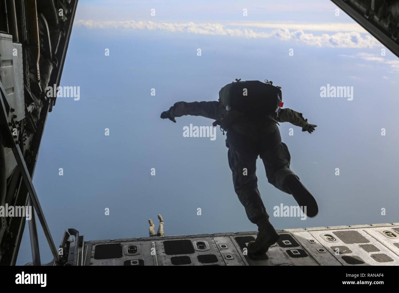 A Marine dives from the back of a Lockheed C-130 Hercules to land at a ...