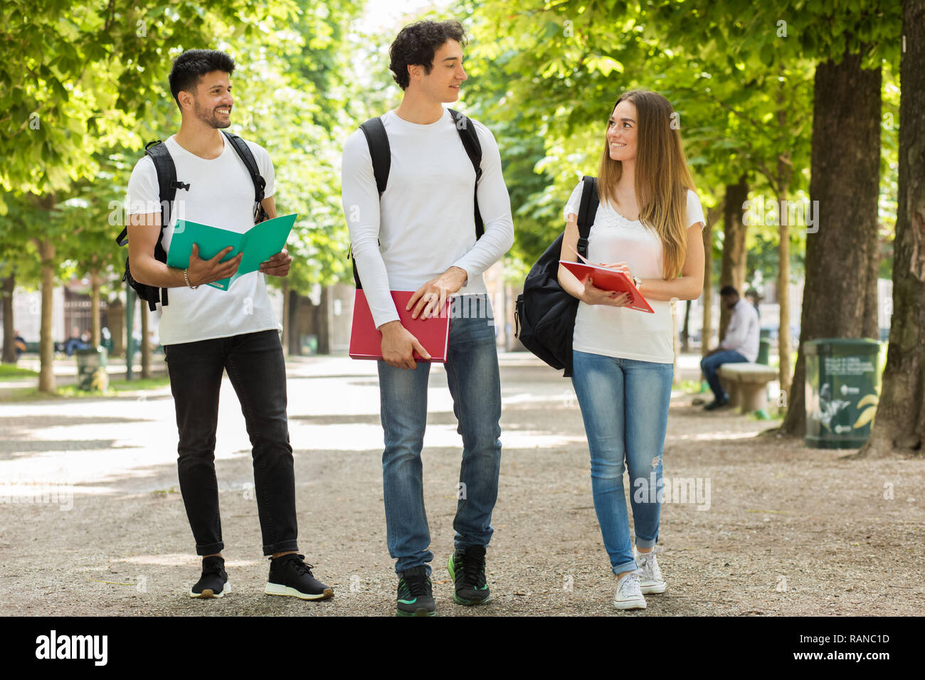 Three students talking to each other outdoor in a college courtyard ...