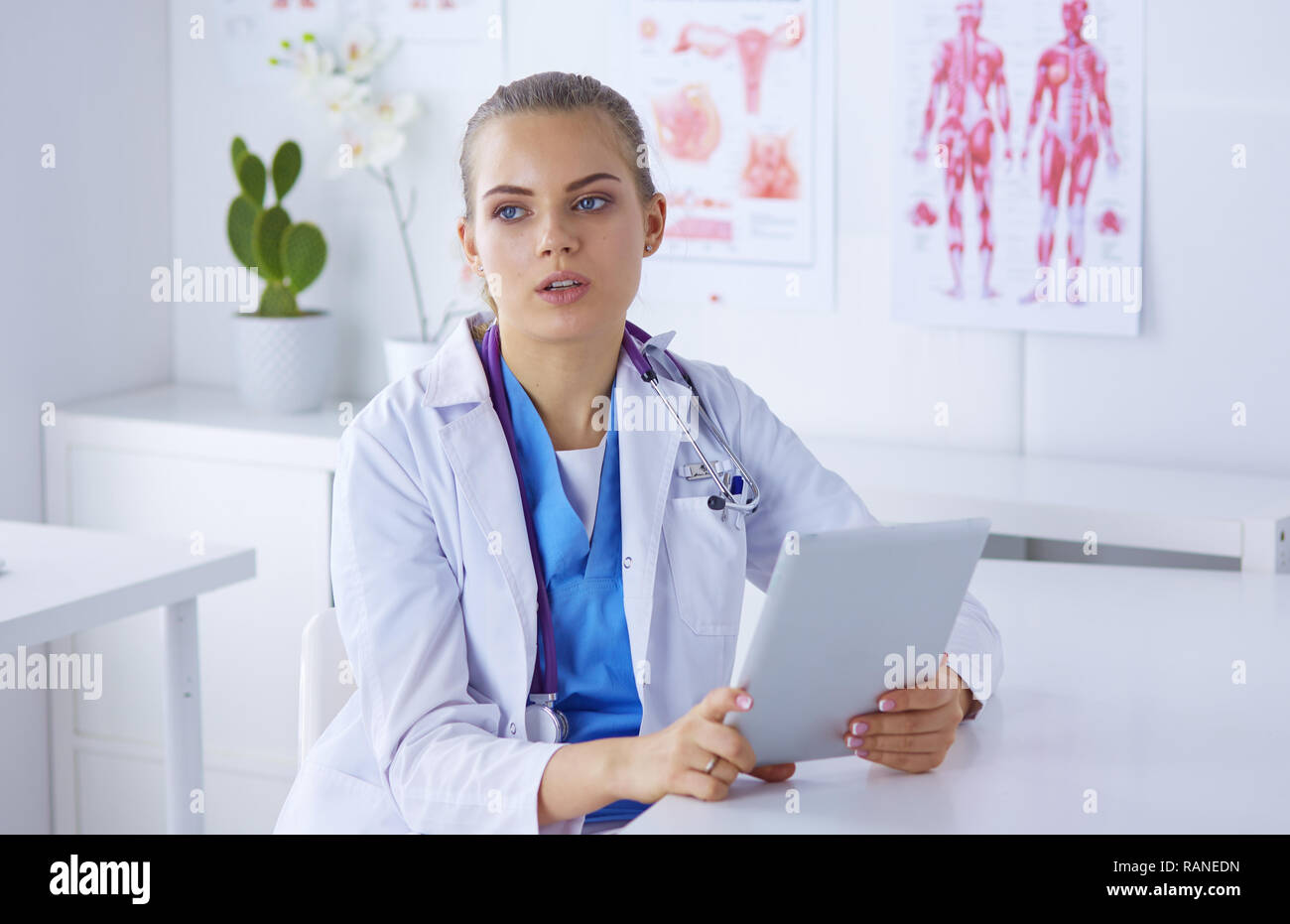 A young female doctor at a desk in the office. The concept of health ...