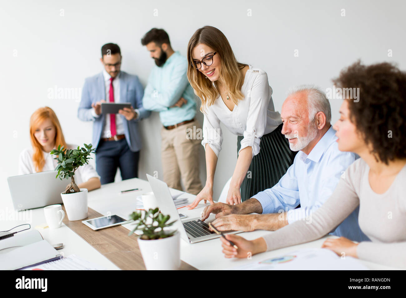View at group of young multiracial business people around table during ...