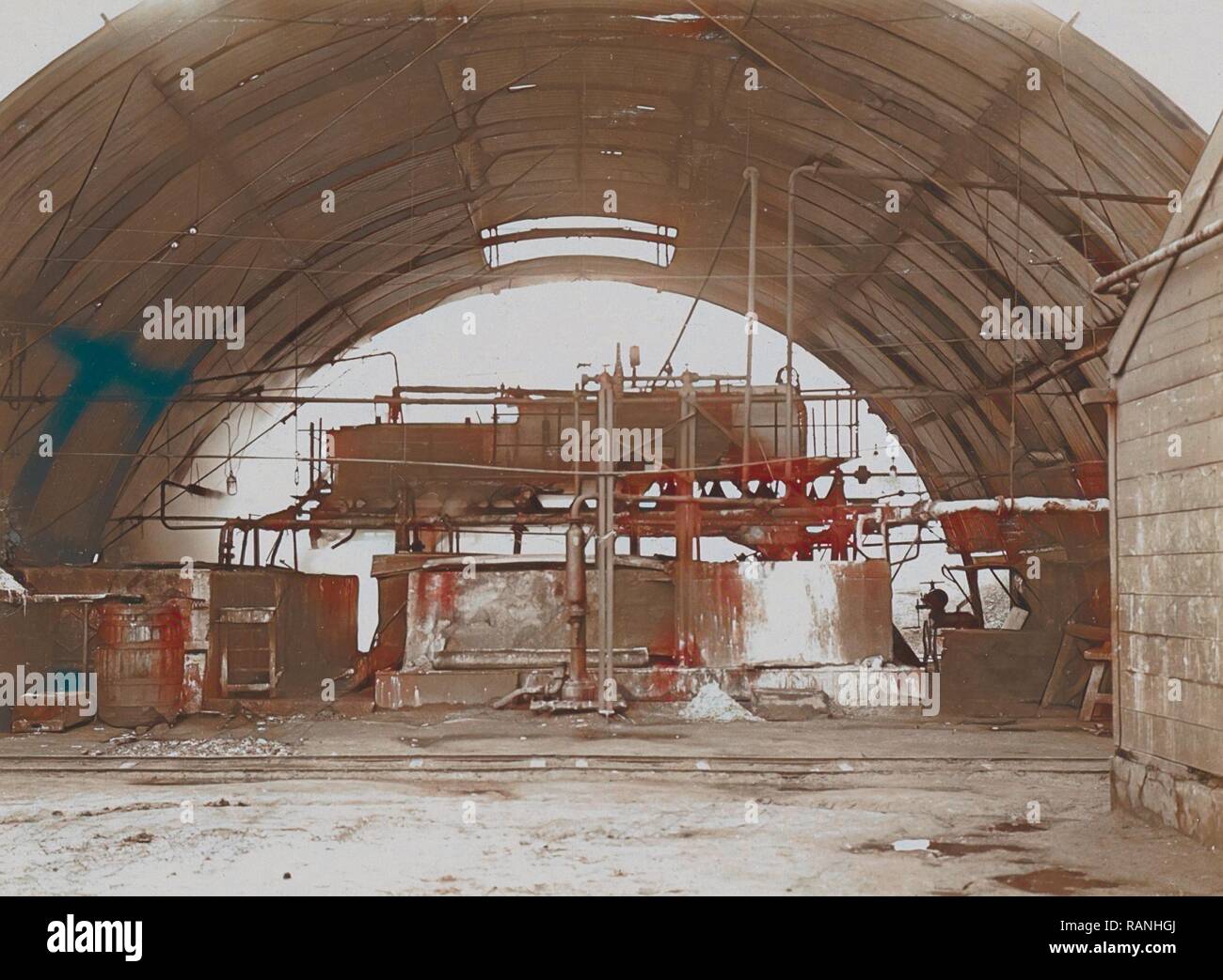 Interior of a half-round factory with a machine and pipe lines ...