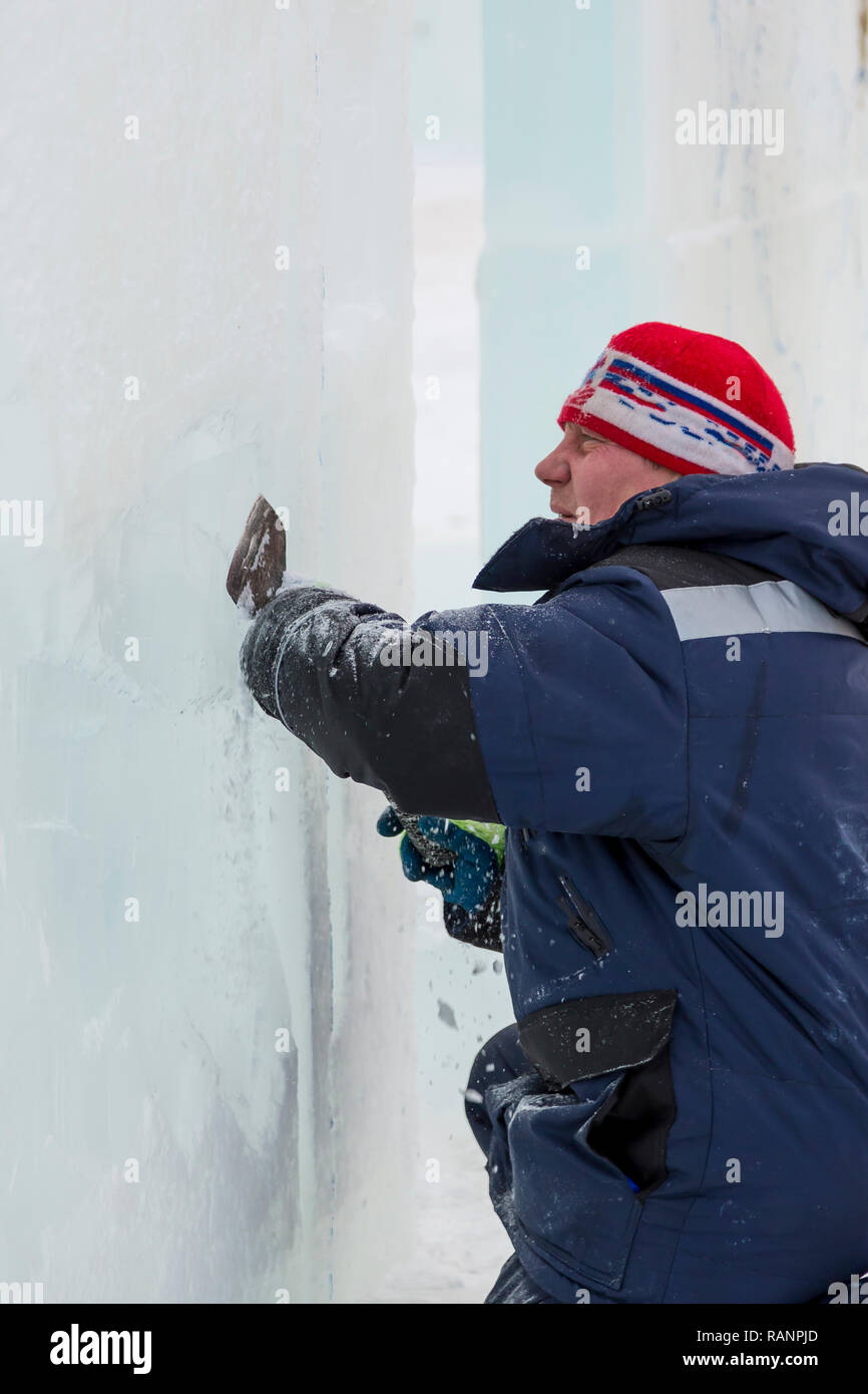 The sculptor cuts an ice figure for Christmas from a block of ice with ...