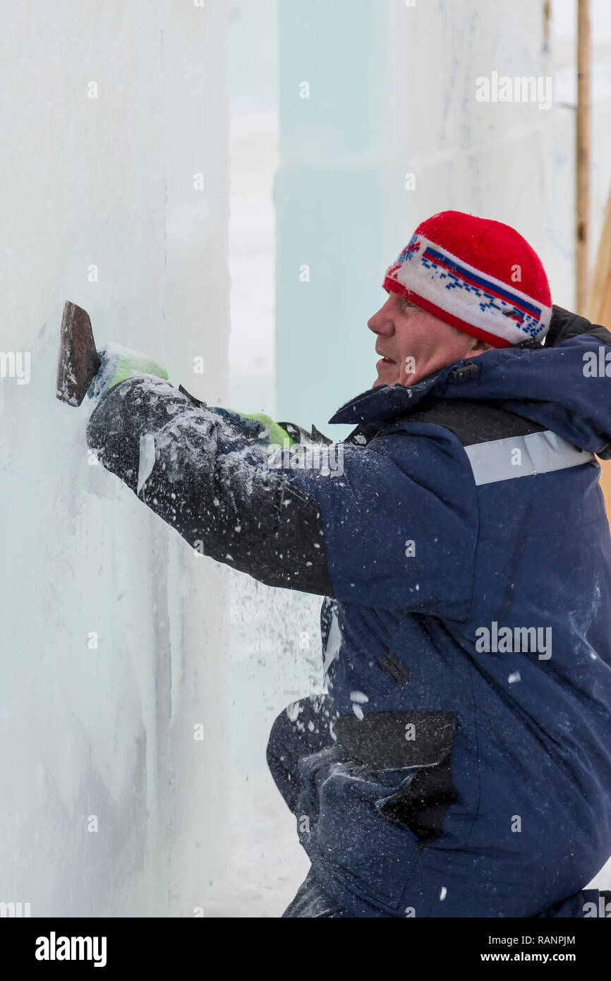 The sculptor cuts an ice figure for Christmas from a block of ice with ...