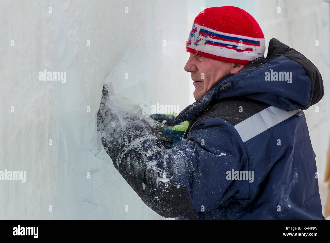 The sculptor cuts an ice figure for Christmas from a block of ice with ...