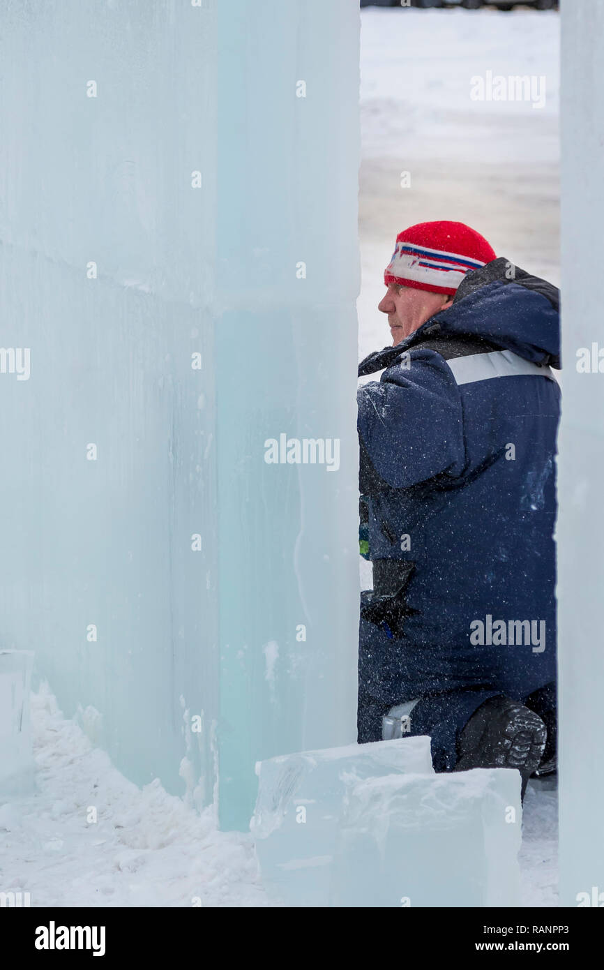 The sculptor cuts an ice figure for Christmas from a block of ice with ...