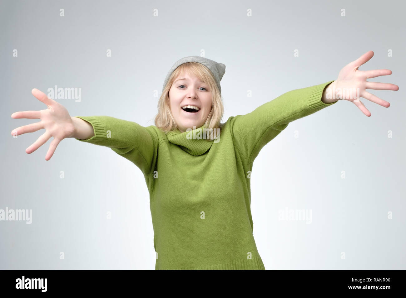 Young woman in green sweater smiling and saying hello Stock Photo - Alamy