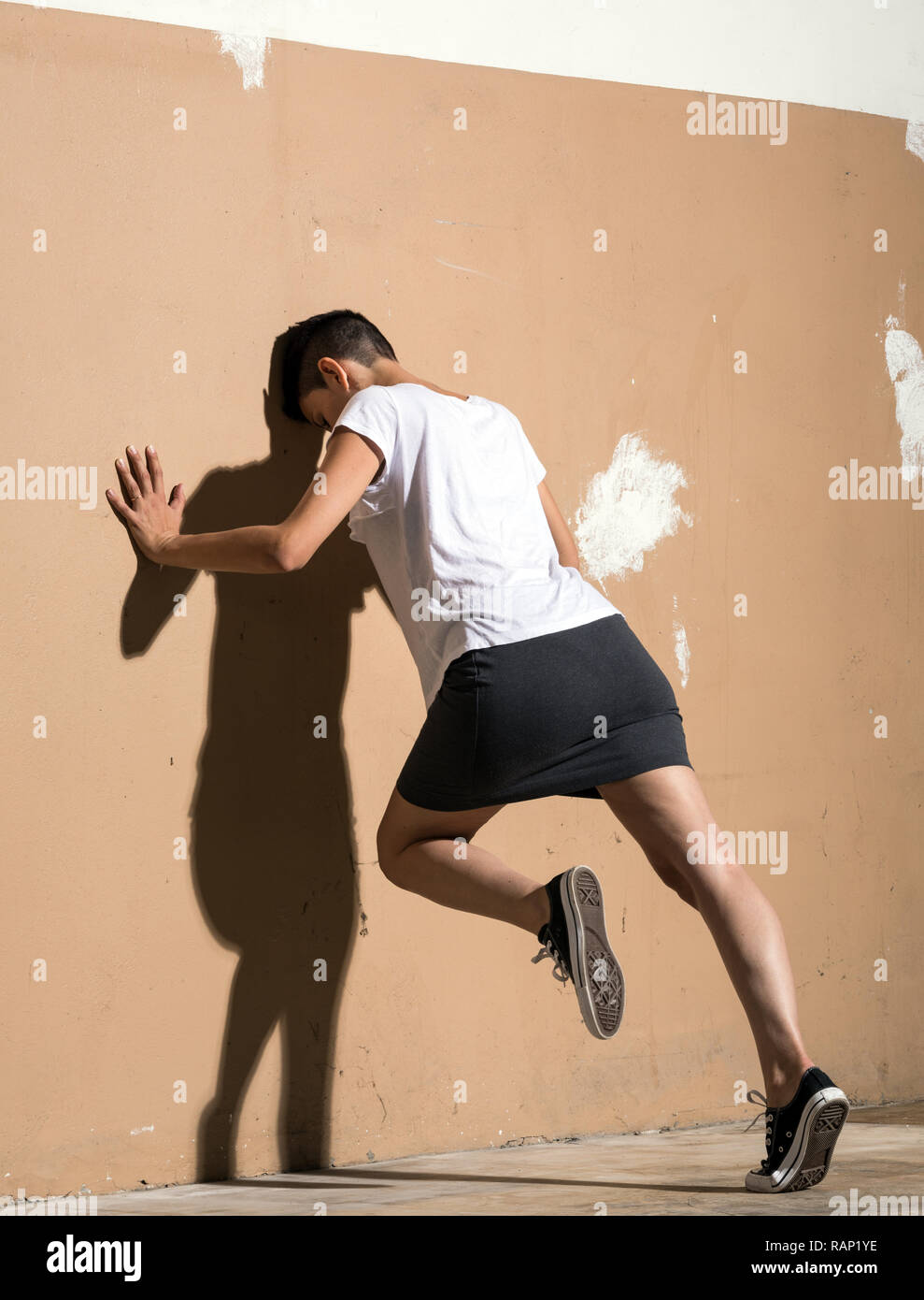 A young woman push the wall and there is a big shadow about the body ...