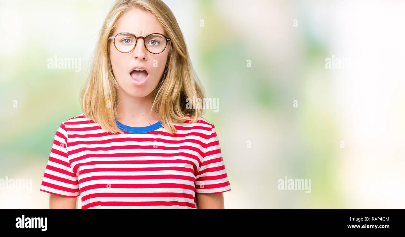 Beautiful young woman wearing glasses over isolated background In shock ...