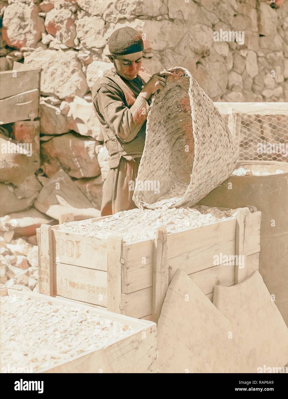 Ground flint. a man emptying a basket of gound flint into a wooden box ...