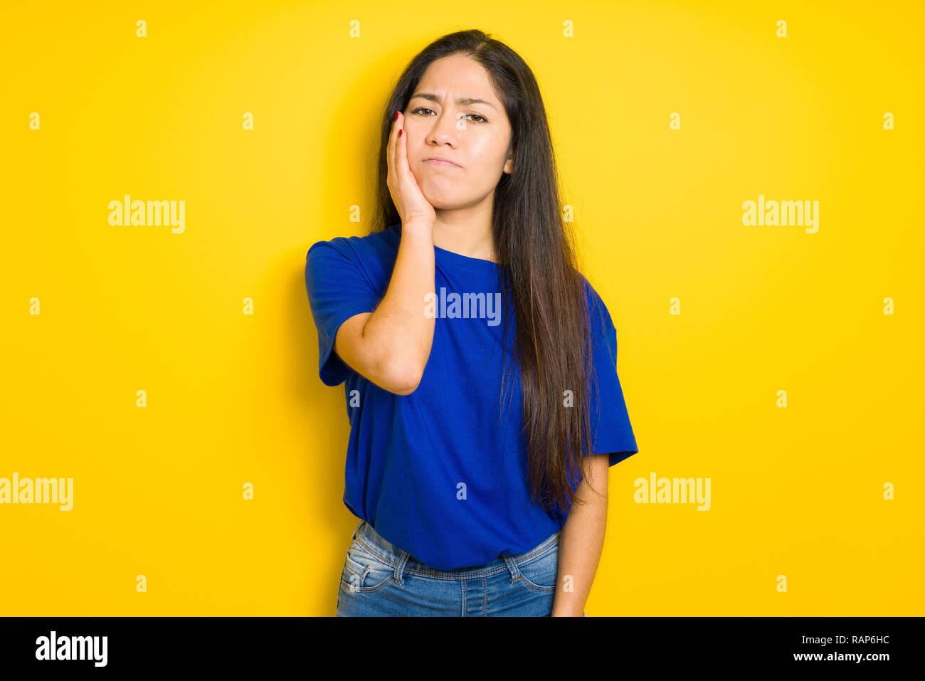 Beautiful brunette woman wearing blue t-shirt over yellow isolated ...