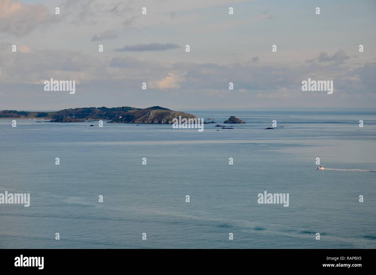 Small boat crossing the water off Jerbourg Point with Herm and Jethou ...