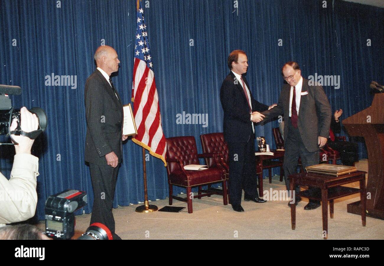 TWO MEN GREETING EACH OTHER WITH A HAND SHACK WITH ANOTHER MAN IN THE ...