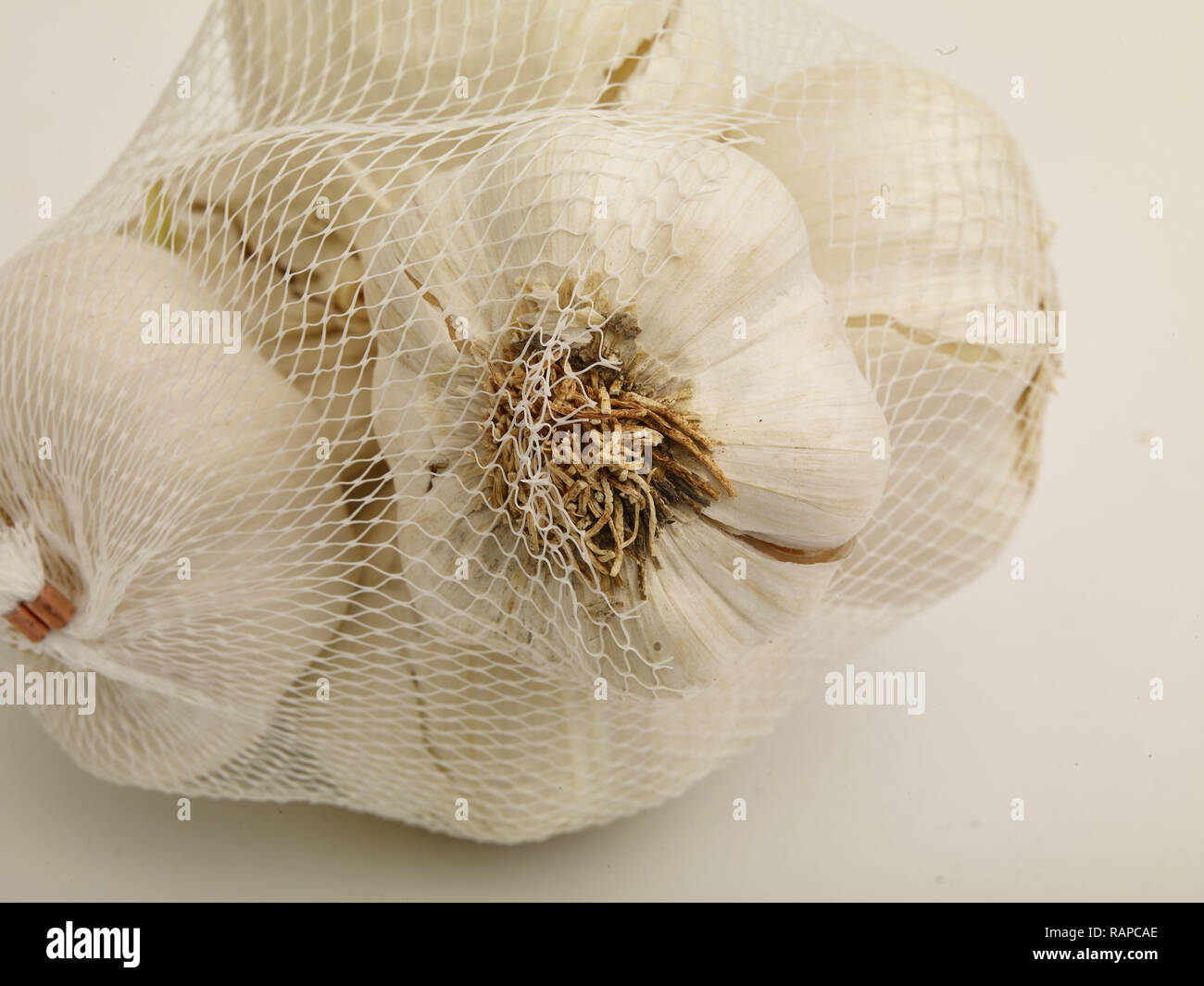 Garlic in net bag on white background food photograph Stock Photo - Alamy