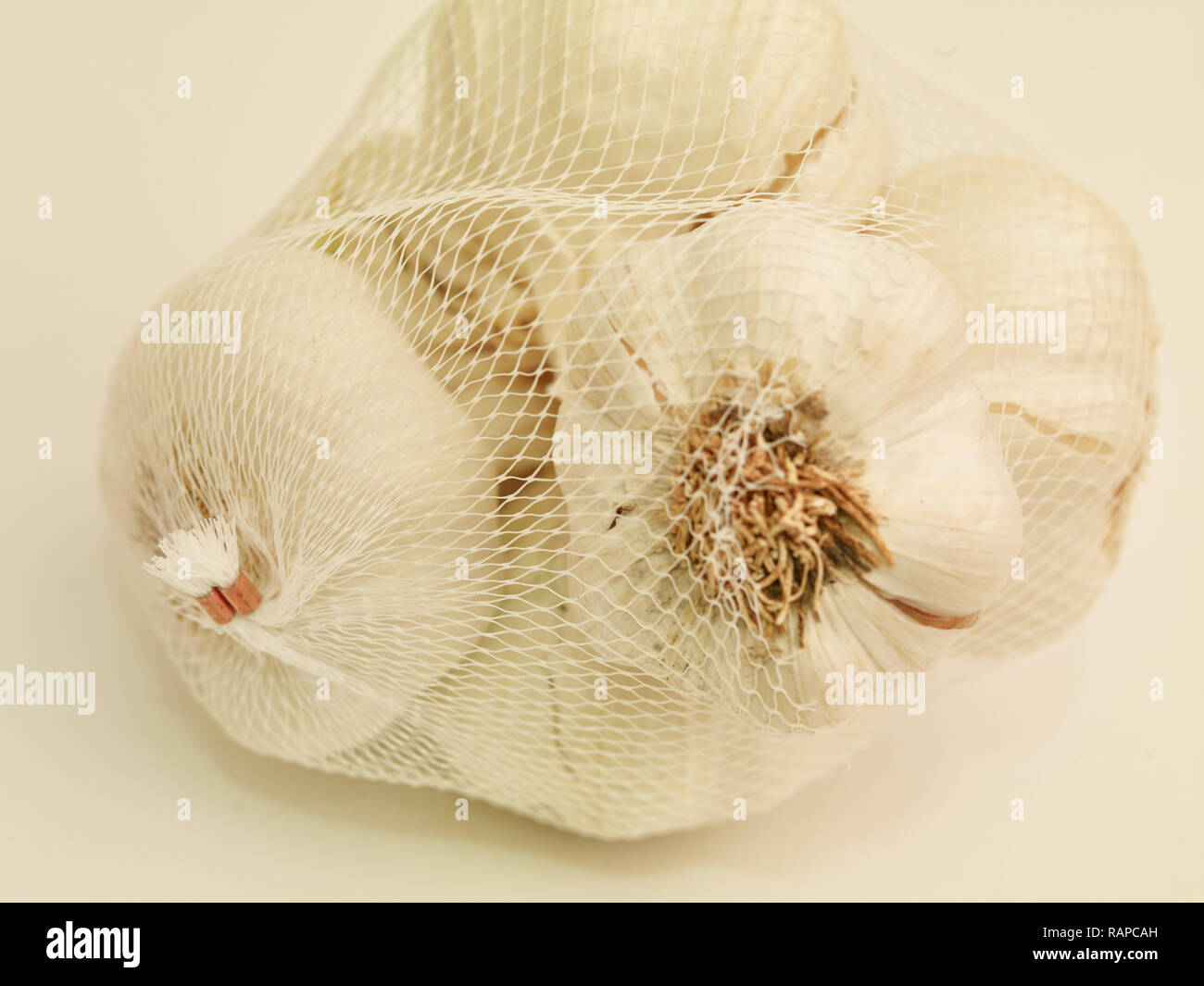 Garlic in net bag on white background food photograph Stock Photo - Alamy