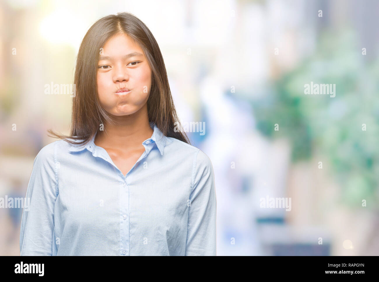 Young asian business woman over isolated background puffing cheeks with ...