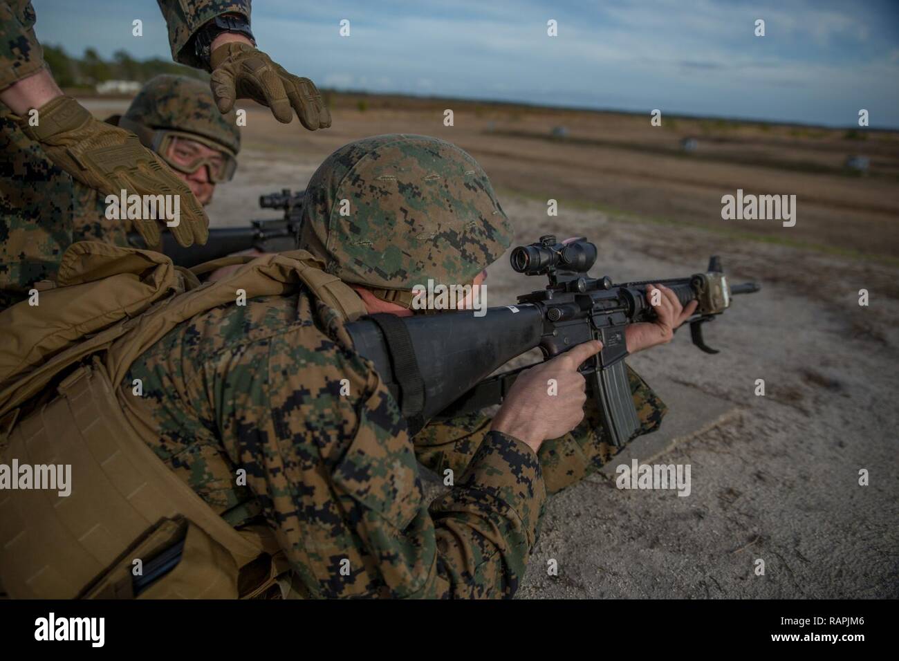 A Marine is corrected on his firing position and prone stance by a ...
