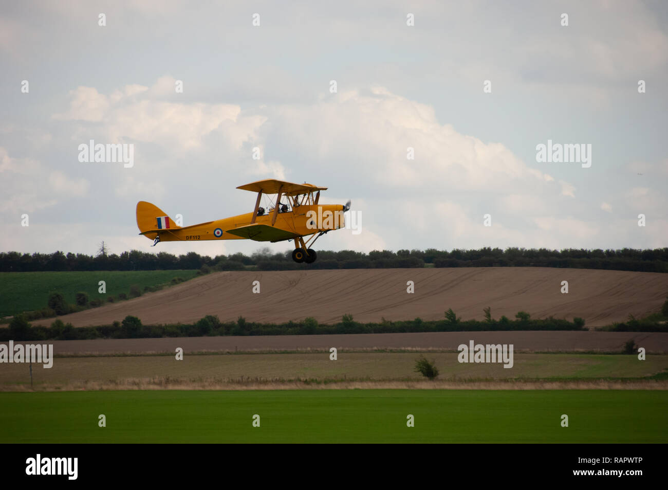 A yellow biplane flies over Duxford Imparial War Museum Stock Photo - Alamy