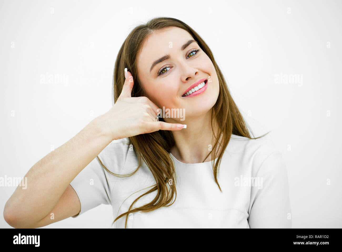 Young happy smiling brunette woman with call me gesture, against white background Stock Photo ...