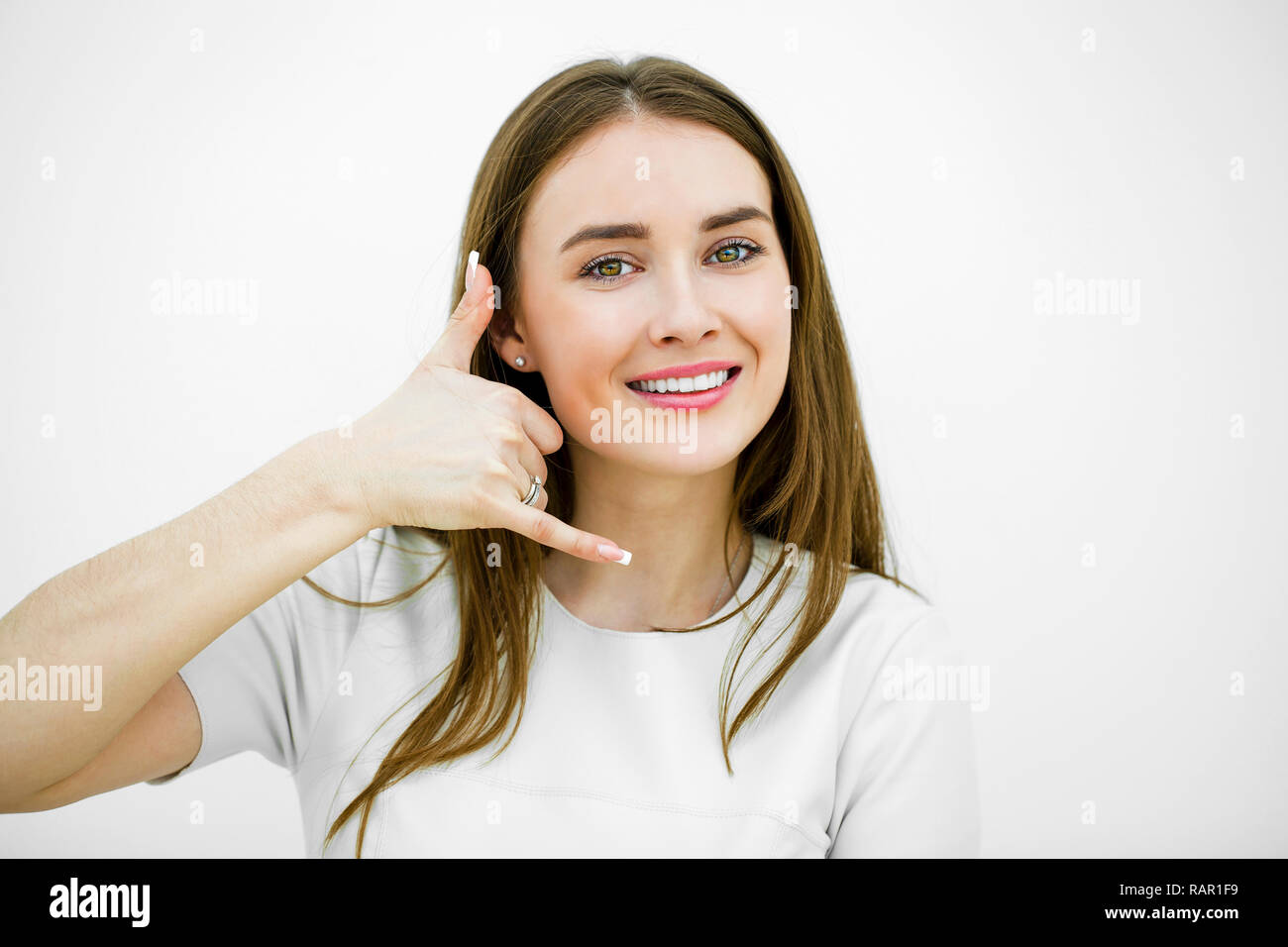 Young happy smiling brunette woman with call me gesture, against white ...