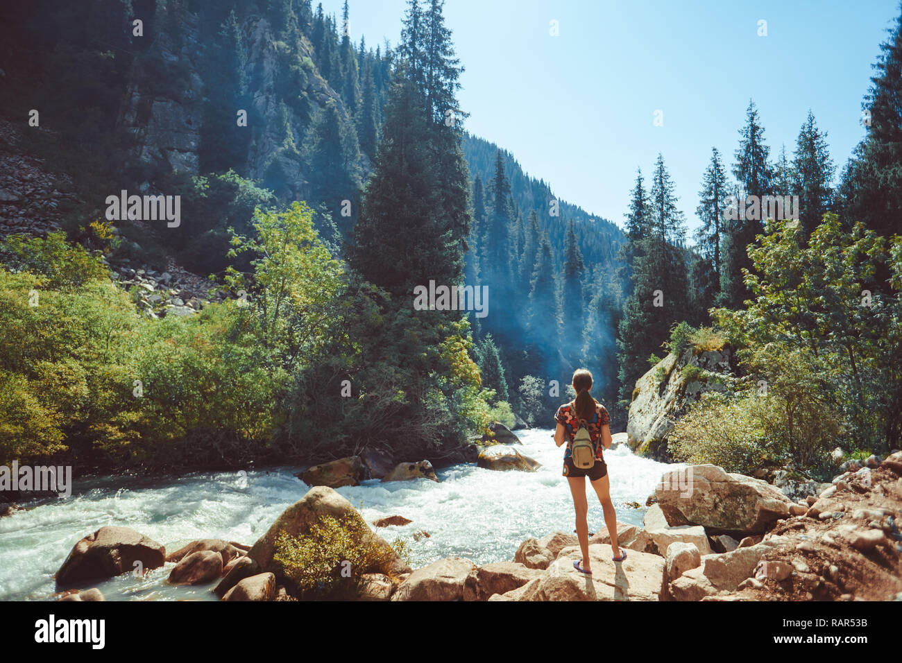 woman traveler with backpack looking at amazing mountains and river ...