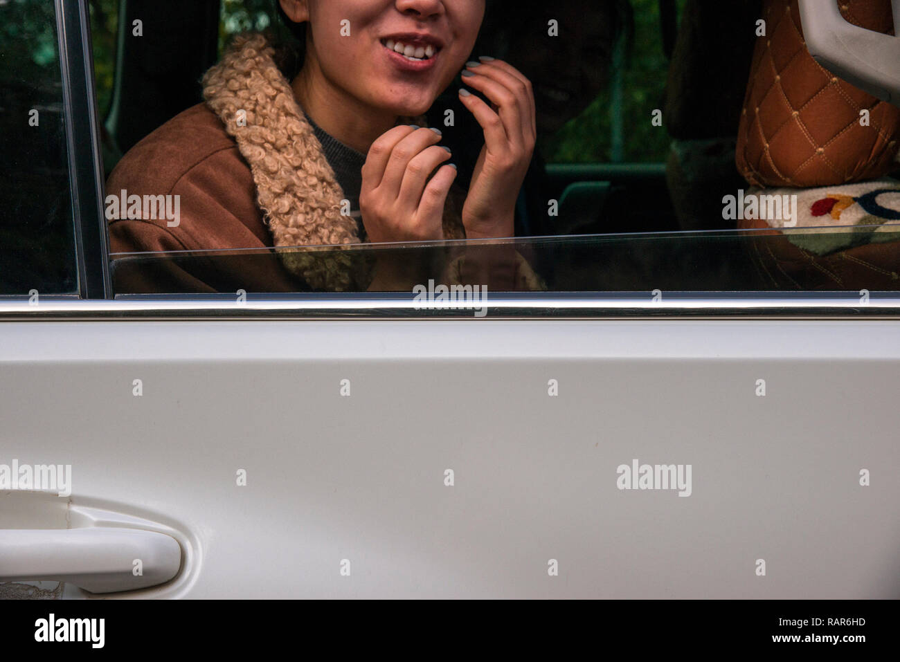 Chinese Woman Seen Through Open Car Window Who Is On Mobile Phone Stock