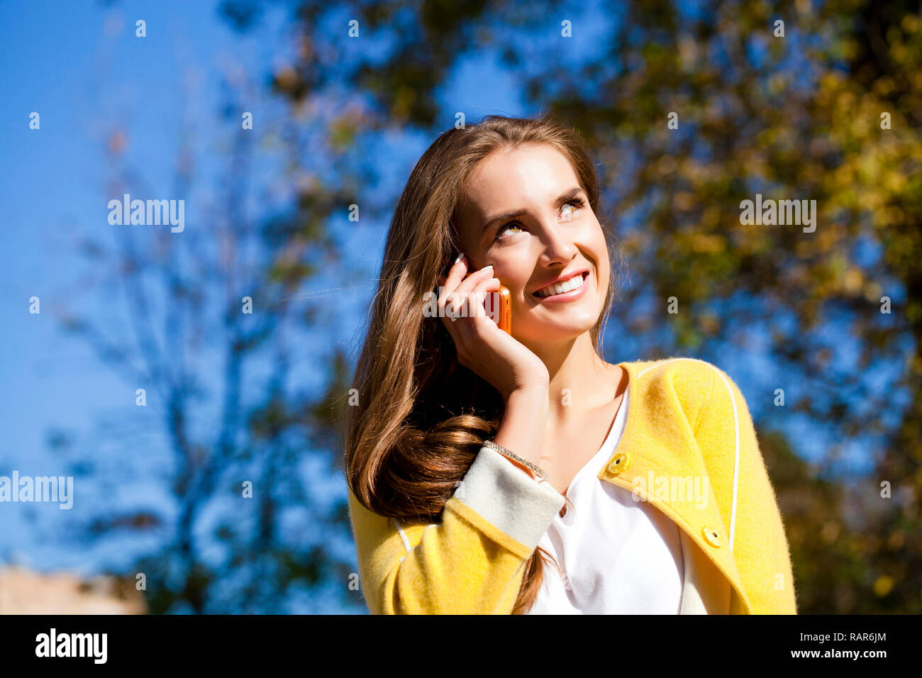 Happy beautiful woman calling by phone in autumn street Stock Photo - Alamy
