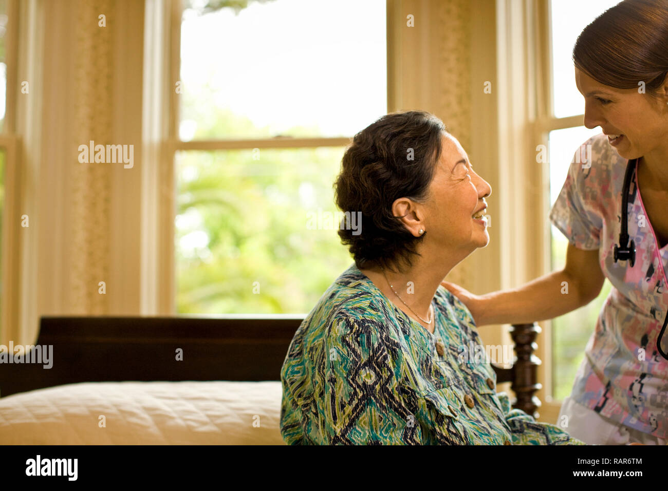 Female nurse smiles and puts a reassuring hand on the shoulder of a ...