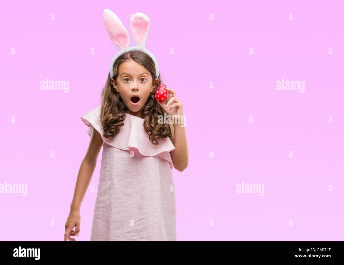 Brunette hispanic girl wearing easter rabbit ears scared in shock with ...