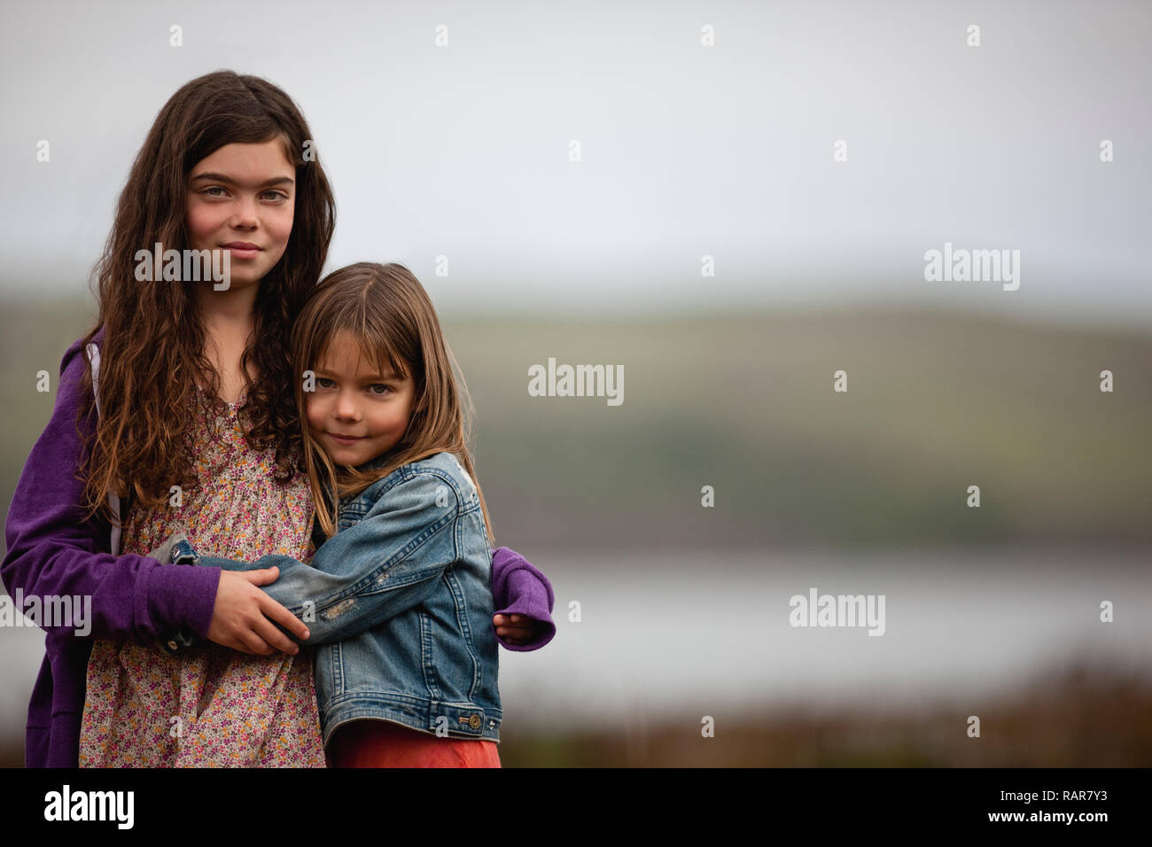 Two girls hug as they pose for a portrait outside Stock Photo - Alamy