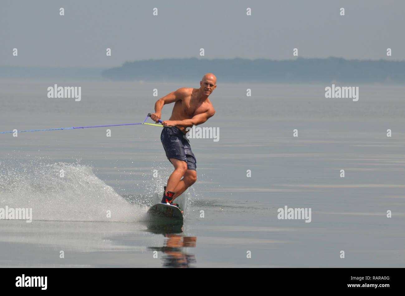 Athletic guy wakeboarding and creating a wake in Maine Stock Photo - Alamy