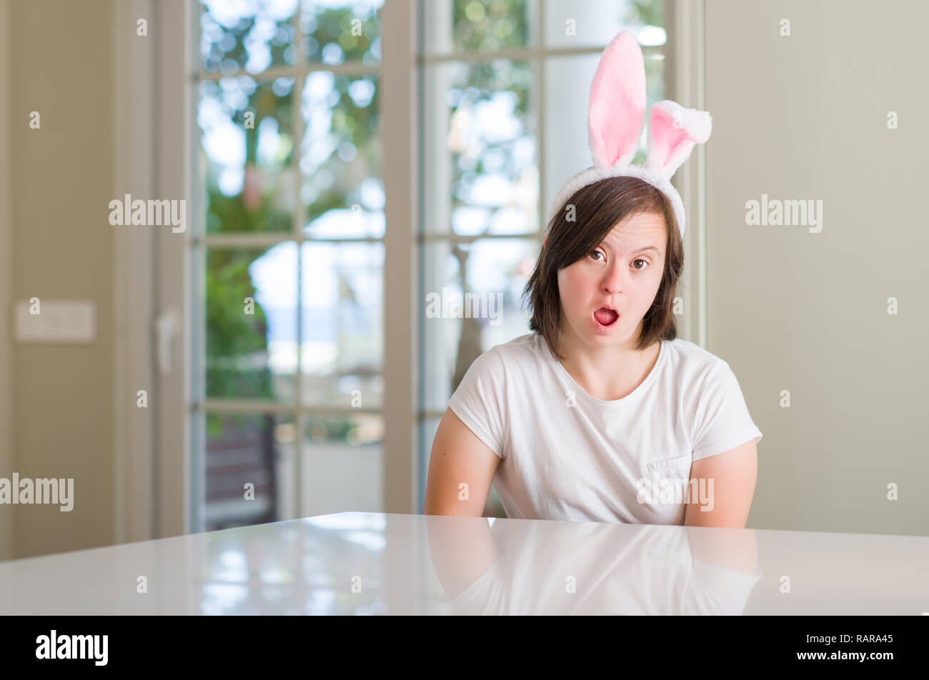 Down syndrome woman at home wearing easter rabbit ears scared in shock ...