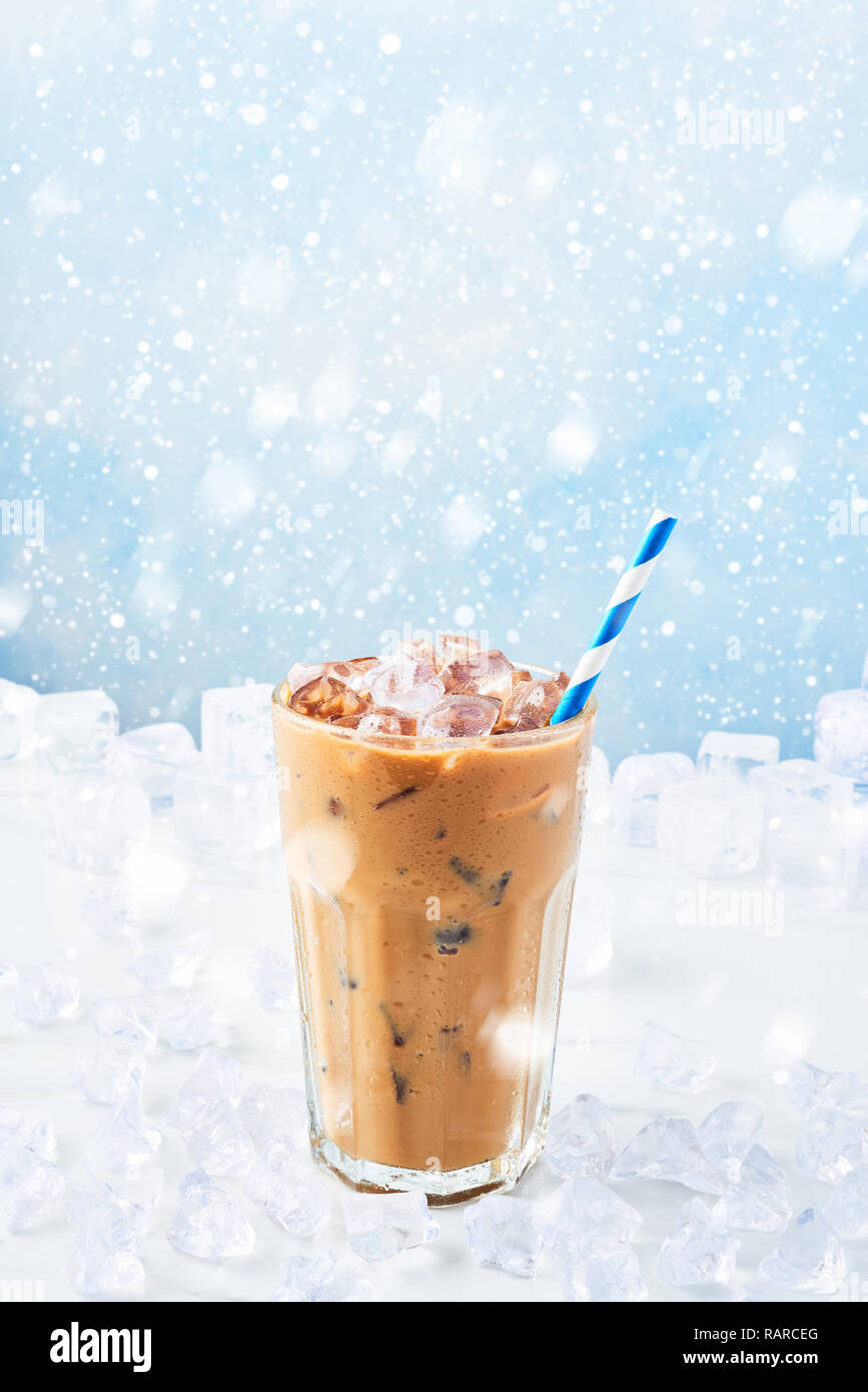 Winter drink ice coffee with cream in a tall glass with straw ...