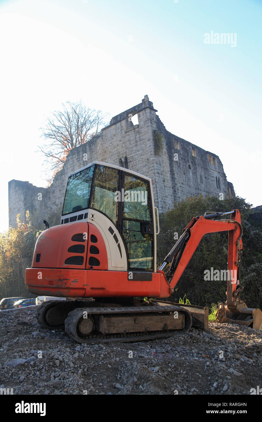 Small excavator on a consruction site hill in front of an ancient ...