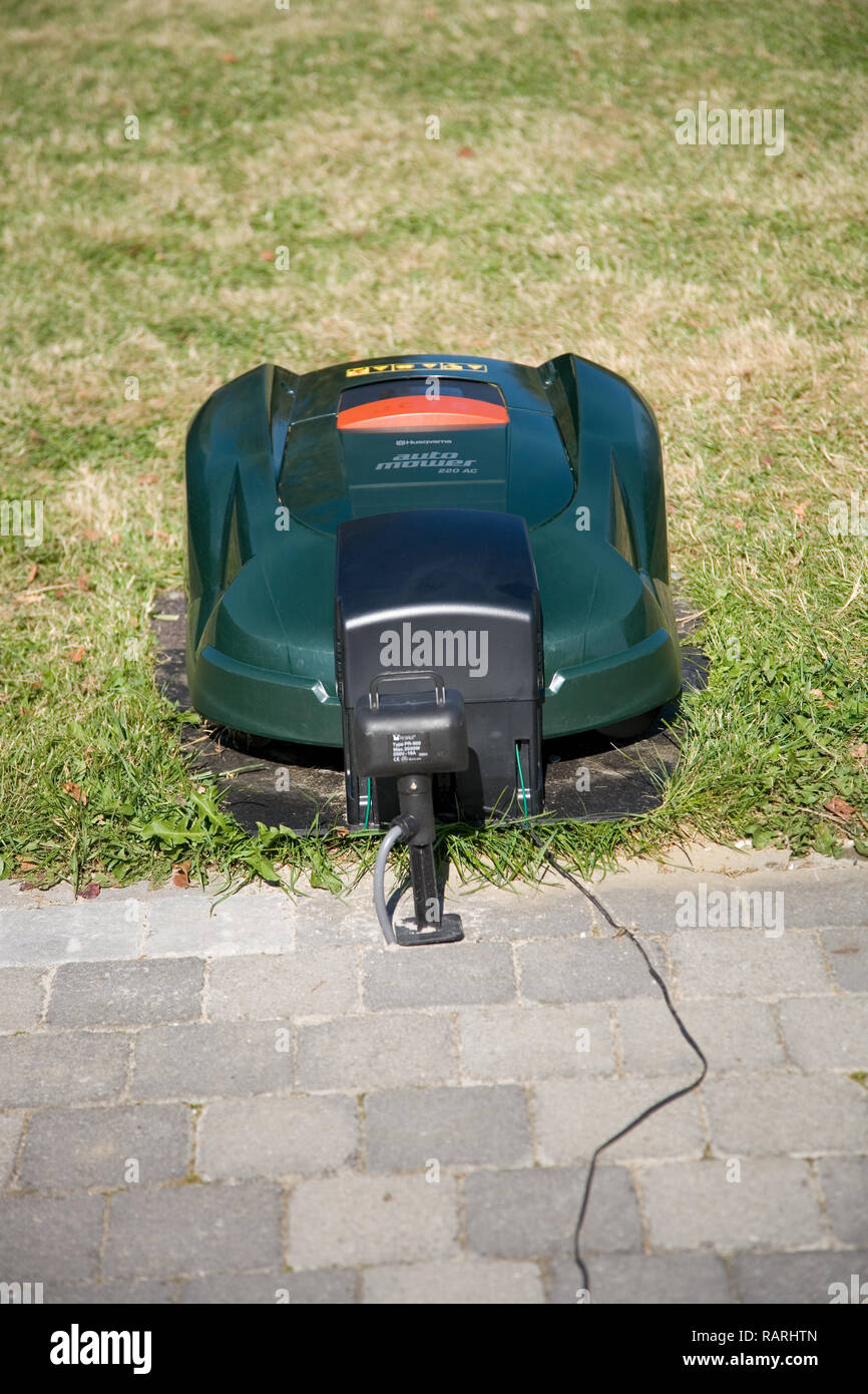 Green automatic robot lawnmower docked in its charging station near a ...