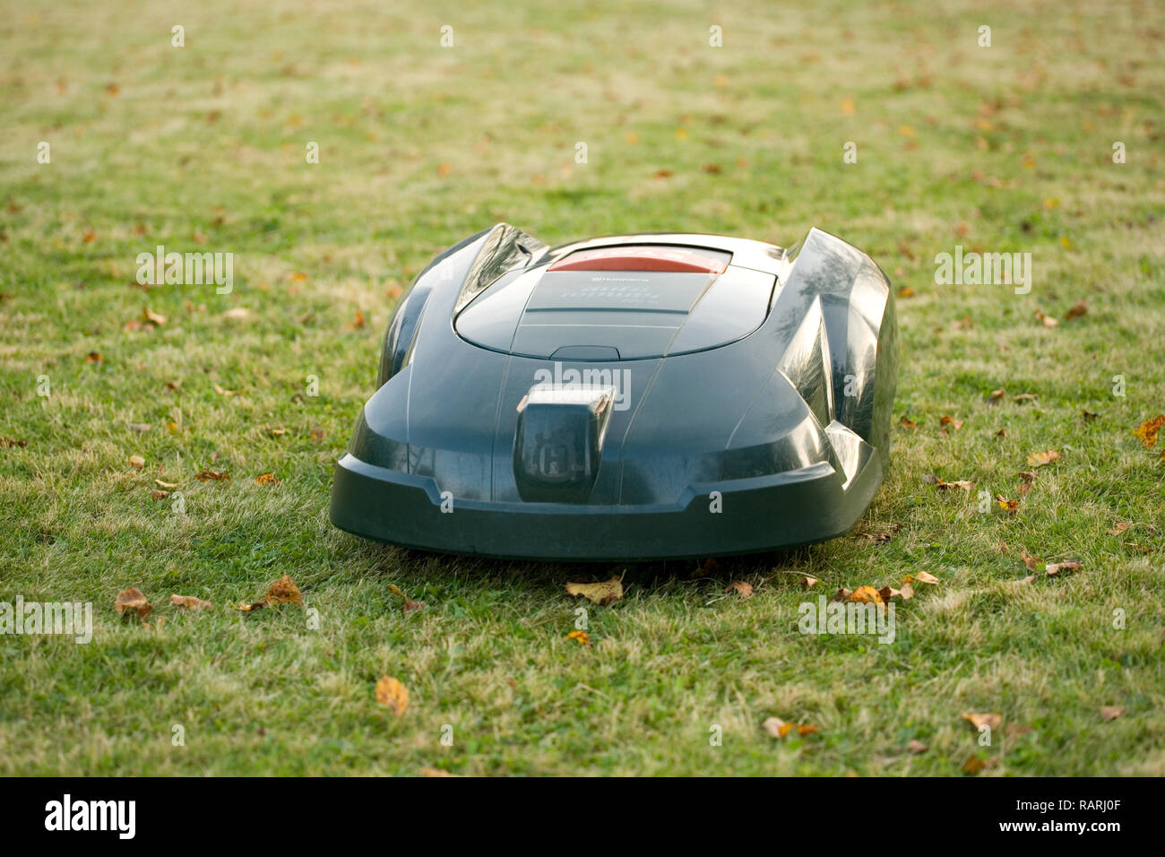 Green automatic robot lawnmower cutting grass head on approaching ...