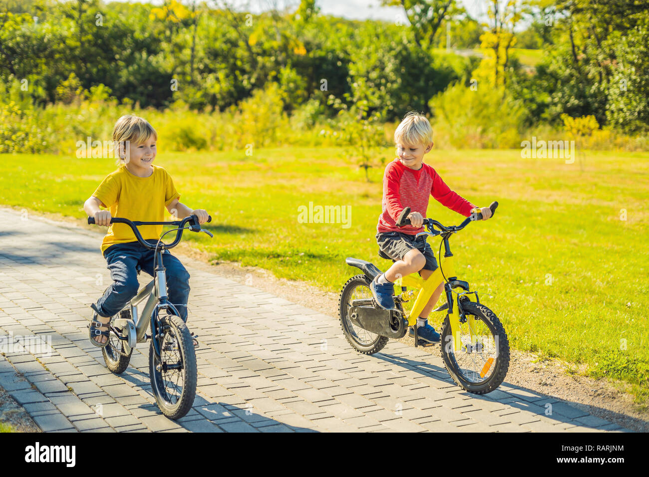 Two happy boys cycling in the park Stock Photo - Alamy