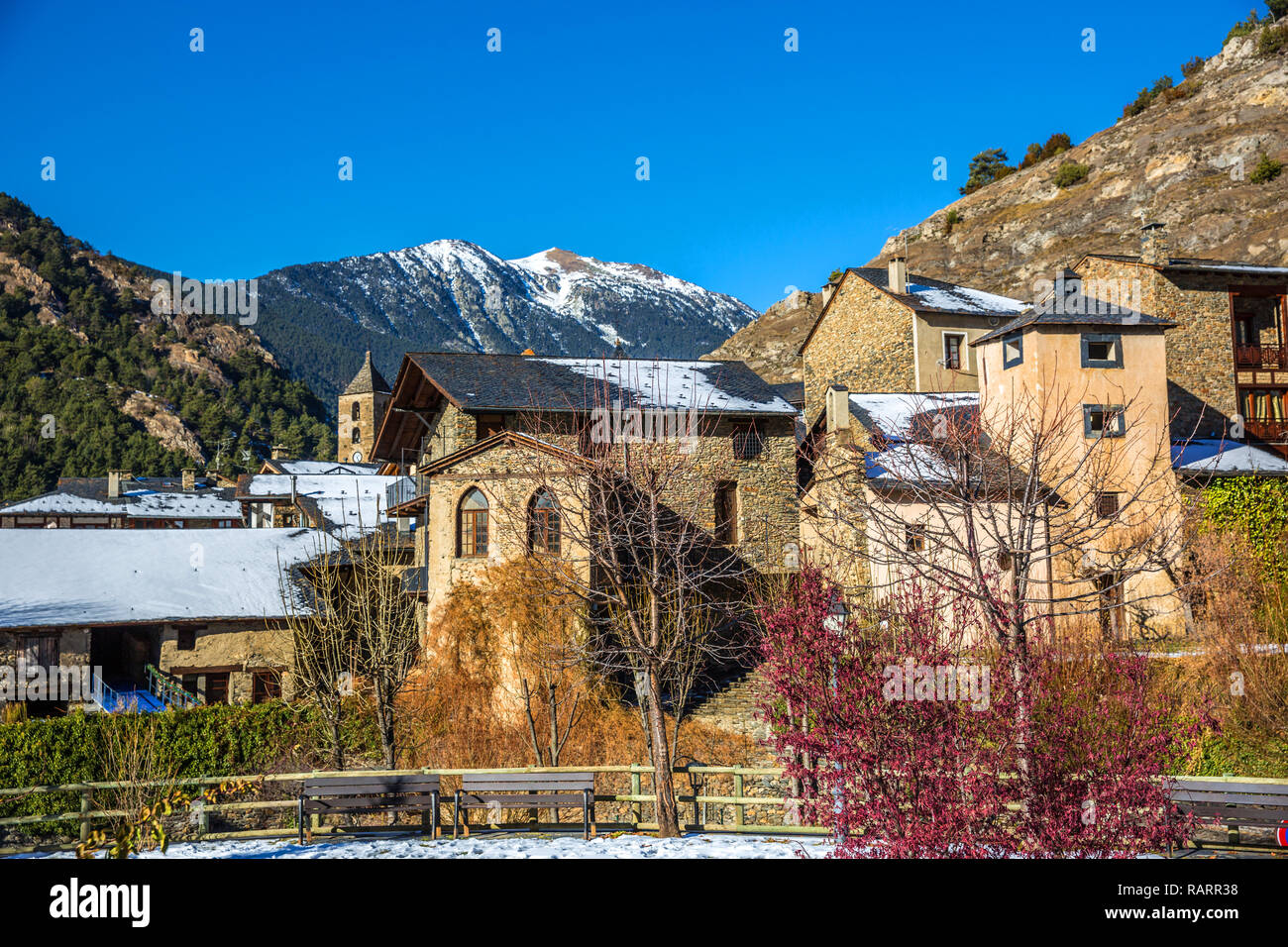 Traditional houses with snow in the roof in a valley with red trees in ...